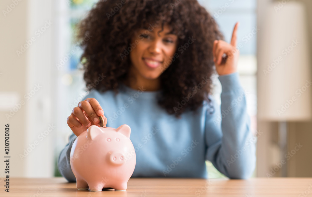 African american woman saves money in piggy bank surprised with an idea ...