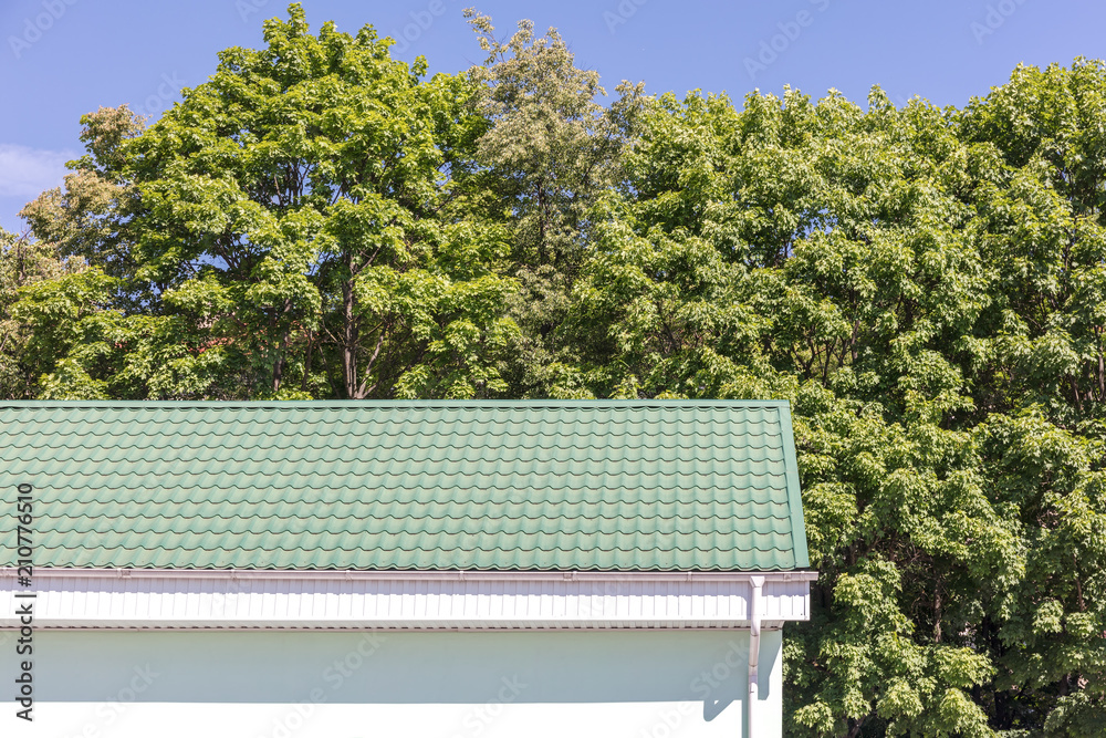 green metal roof and white rain gutter system. new house against green ...