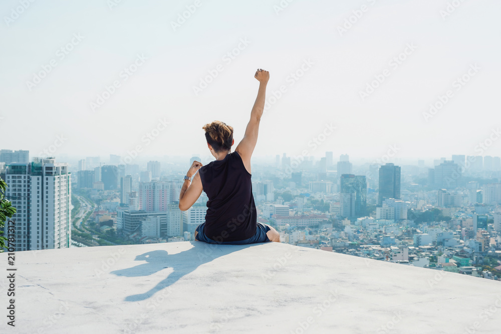 Man sitting on black roof and show hand up with blue sky background and ...