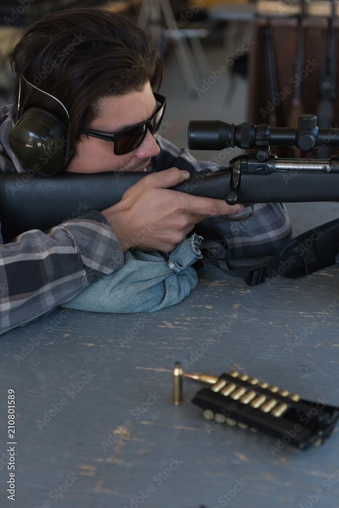 Man aiming sniper rifle at target in shooting range Stock Photo | Adobe ...