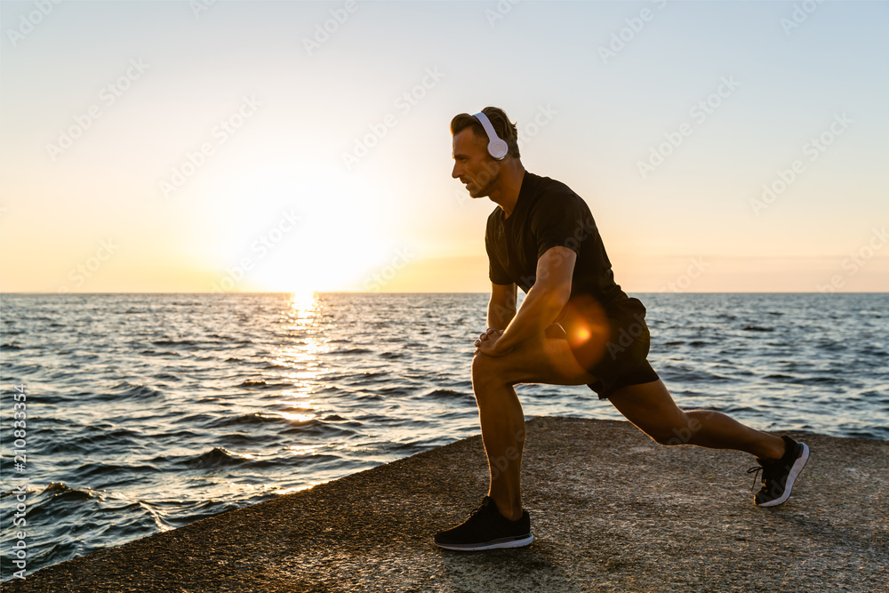 athletic adult man in headphones doing one legged squats during ...