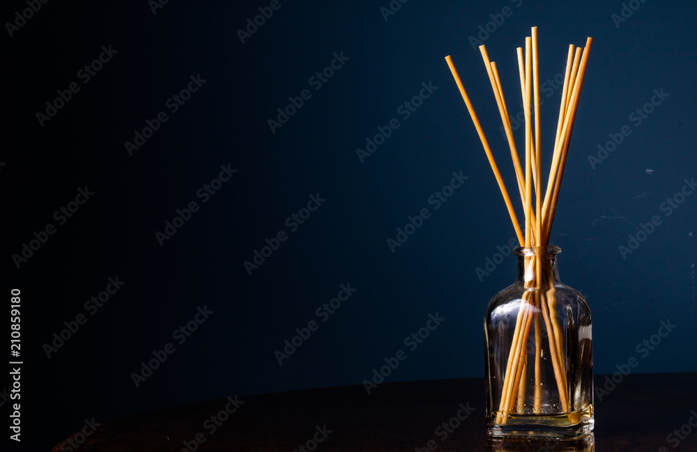 Reed diffusers in a small glass bottle on a table with a navy blue ...