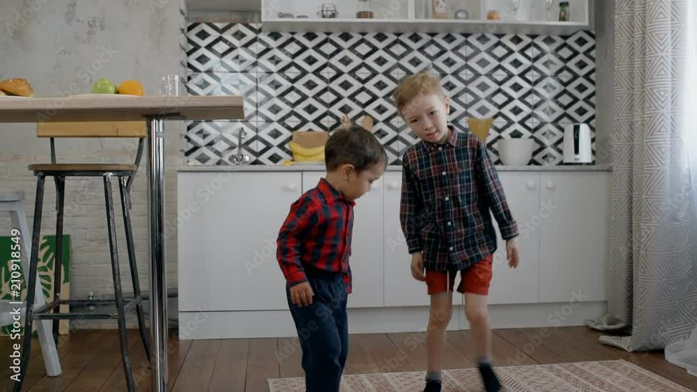 Two boys in checkened shirts dancing at home in the modern kitchen with ...