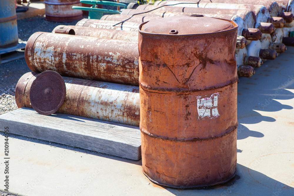 A severely damaged 55-gallon steel drum. Steel drum is rusty, scratched ...