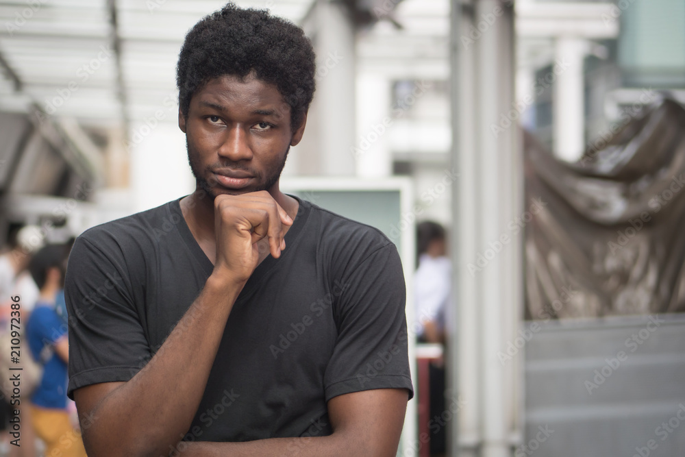 Thoughtful African man thinking; portrait of pensive young adult ...
