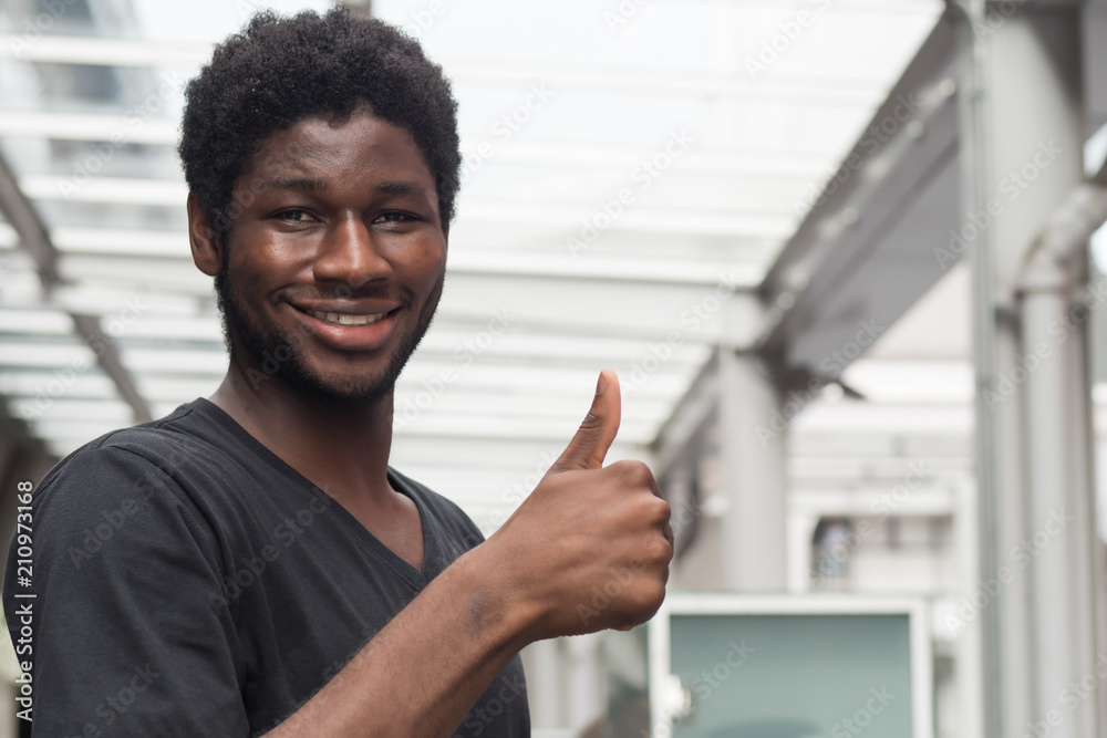 successful african man pointing thumb up; portrait of cheerful smiling ...