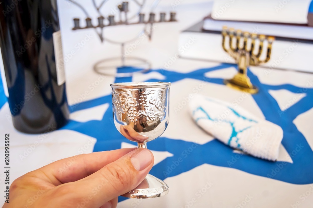 Hand holding a "kiddush" wine blessing cup, a traditional Jewish ...