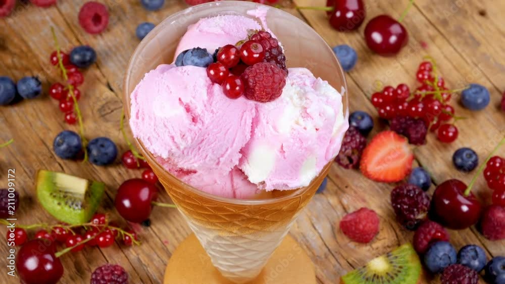 Fruit ice cream in cup rotating on wooden table full of summer forest ...