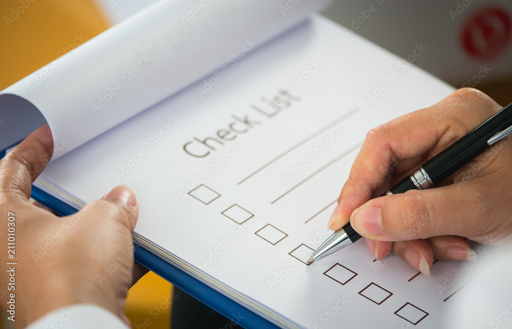 Close- up hand holding pen on check list paper and the format for ...