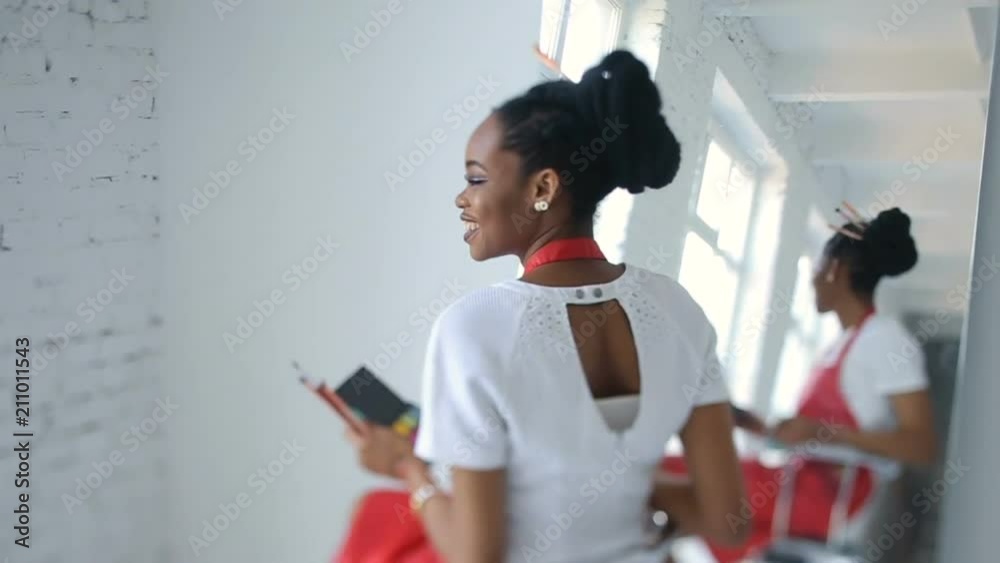 Positive smiling african beautician is holding the set of brushes and ...