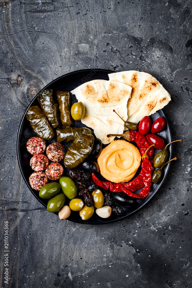 Middle Eastern meze platter with pita, olives, hummus, stuffed dolma ...