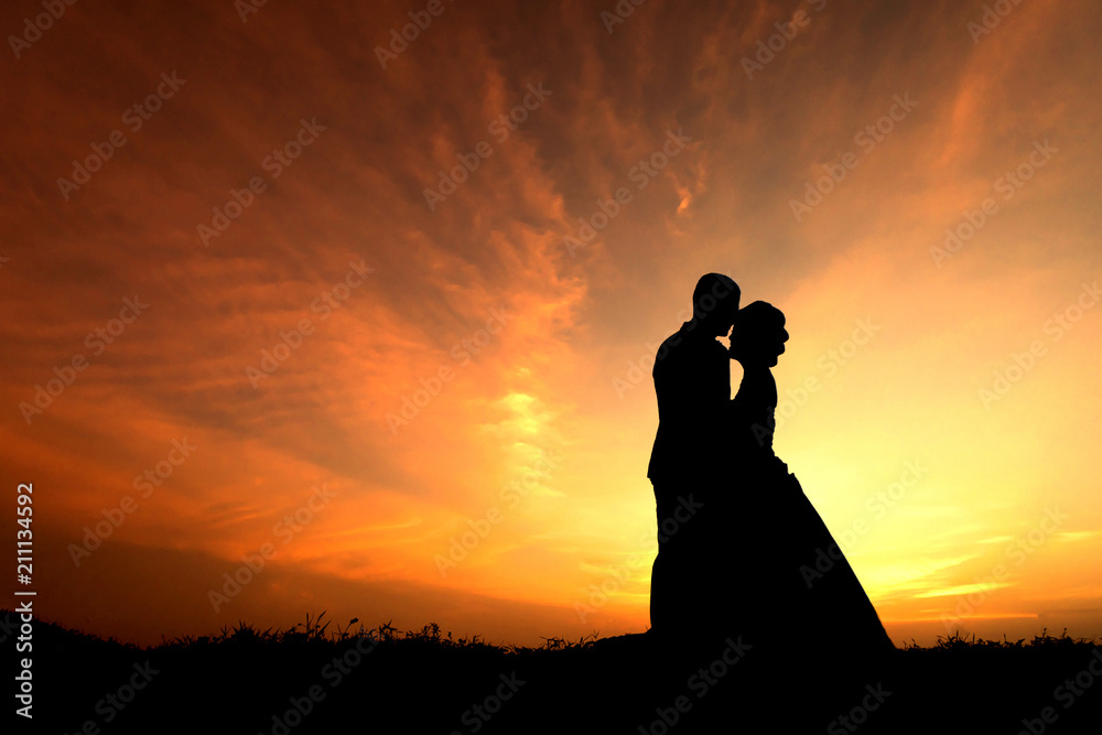 Silhouette two young lovers standing on the hill and kissing in wedding ...