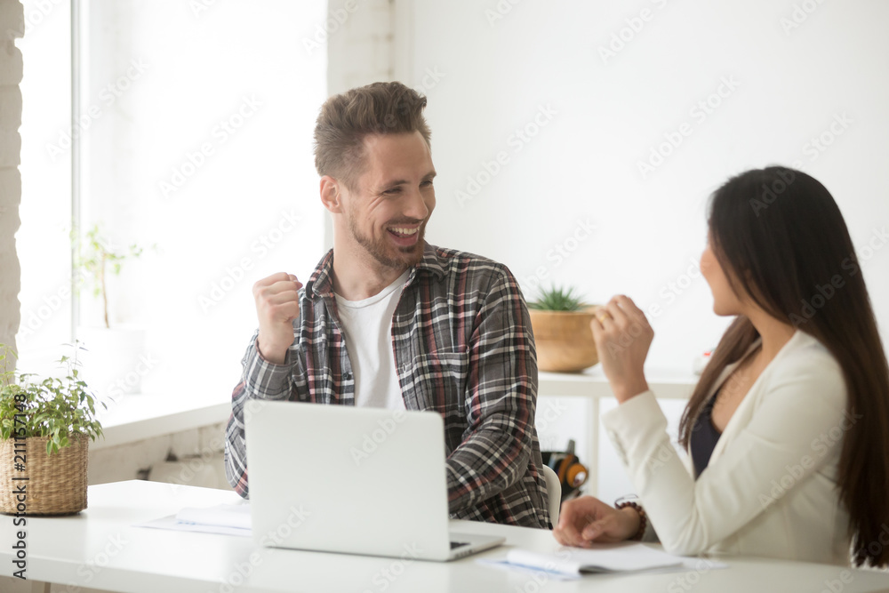 Excited colleagues smiling because of shared goal achievement or ...