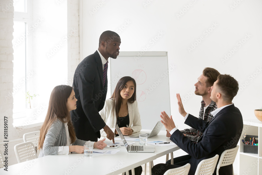 Angry African American worker shouting at Caucasian colleague, blaming ...