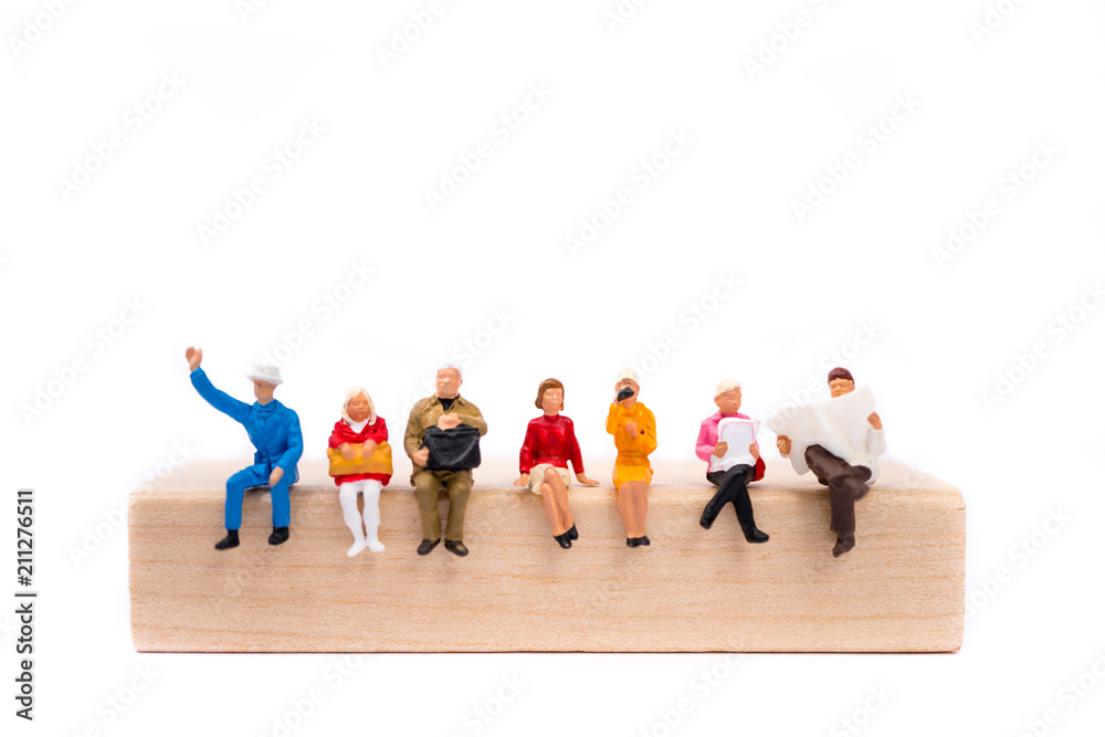 Miniature people sitting on wooden block isolated on white background ...