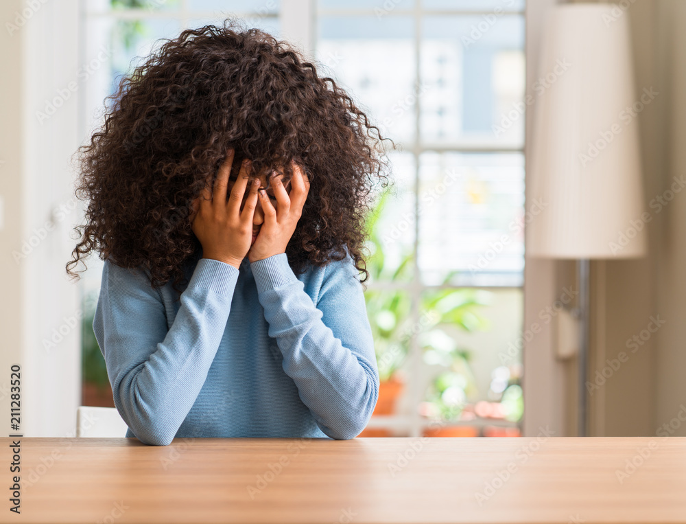 African american woman at home with sad expression covering face with ...