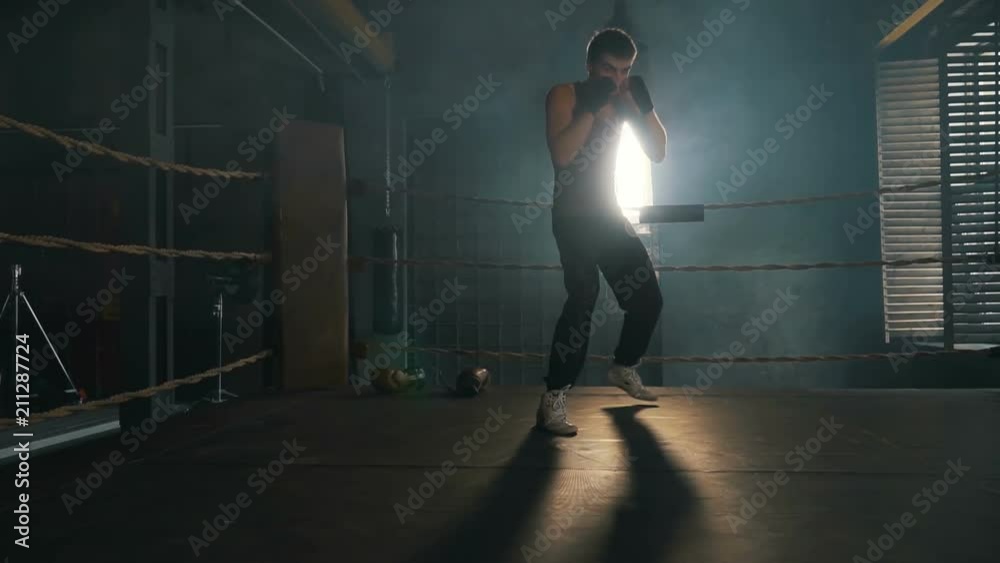 Adult man crouch and boxing on the ring with yellow ropes in industrial ...