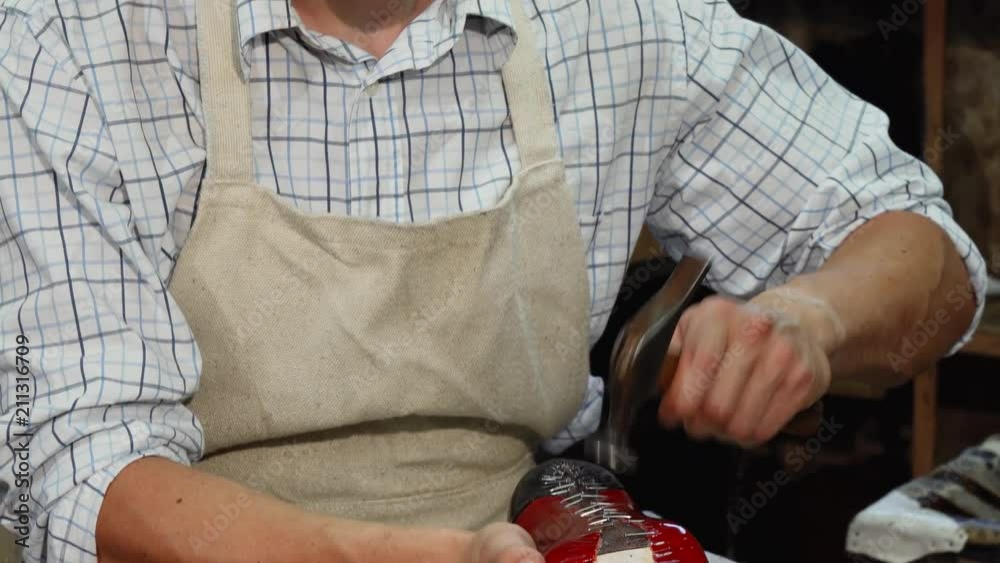 Sliding shot of a professional male shoemaker at work. Young craftsman ...