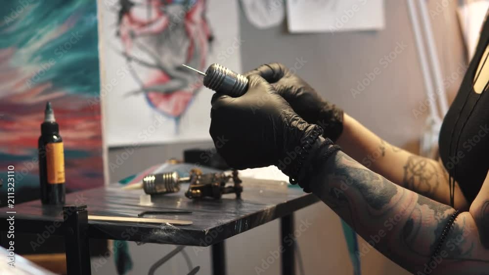 tattoo artist collects the tattoo machine. girl tattoo master prepares ...