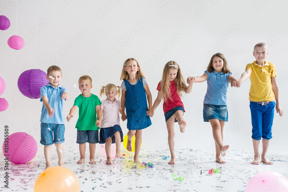 Group of seven 7 children hold hands and jump play with air balloons ...