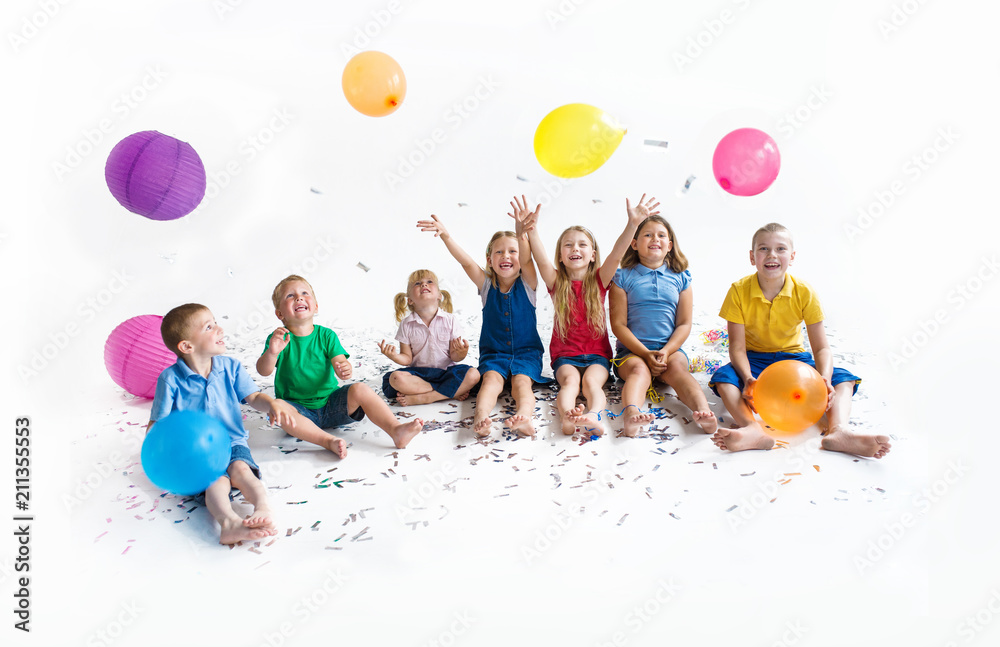 Group of seven 7 children sit on the floor and play with air balloons ...