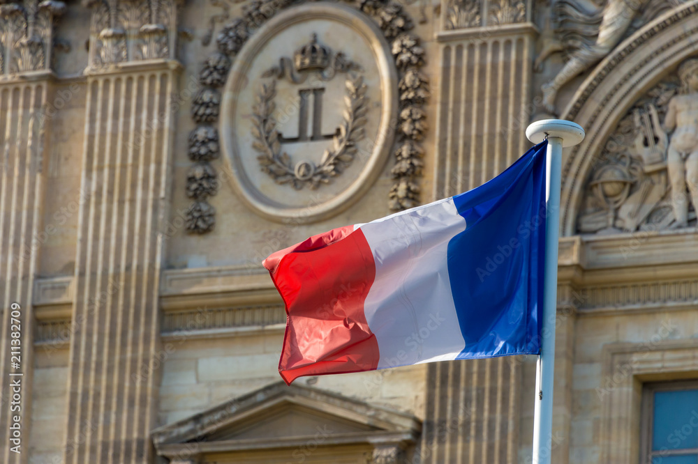 French flag waving in front of the facade of the Louvre Museum in Paris ...