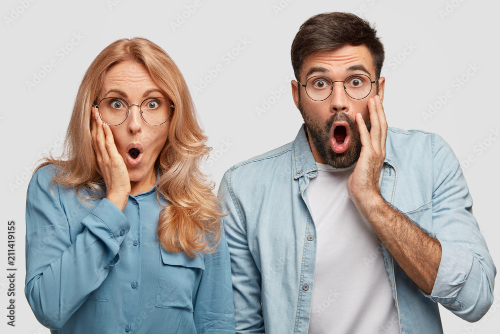 Scraed emotive family couple look with astonishment, being puzzled as ...