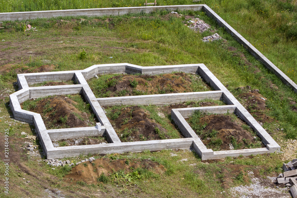 Building site in green field. Trenches dug in ground and filled with ...