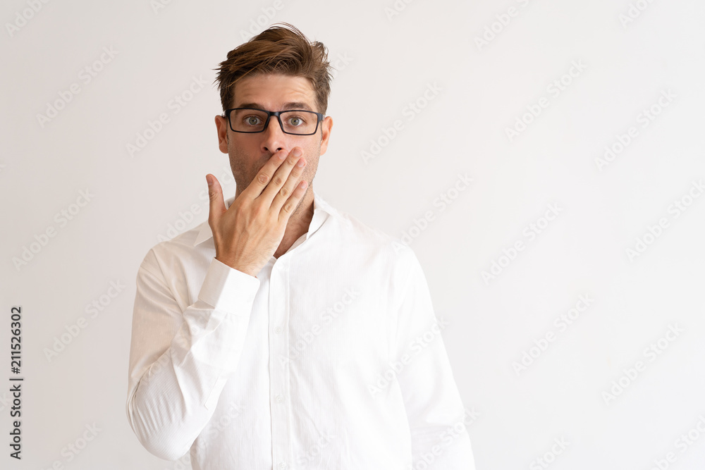 Surprised young man covering mouth with hand. Embarrassed handsome guy ...