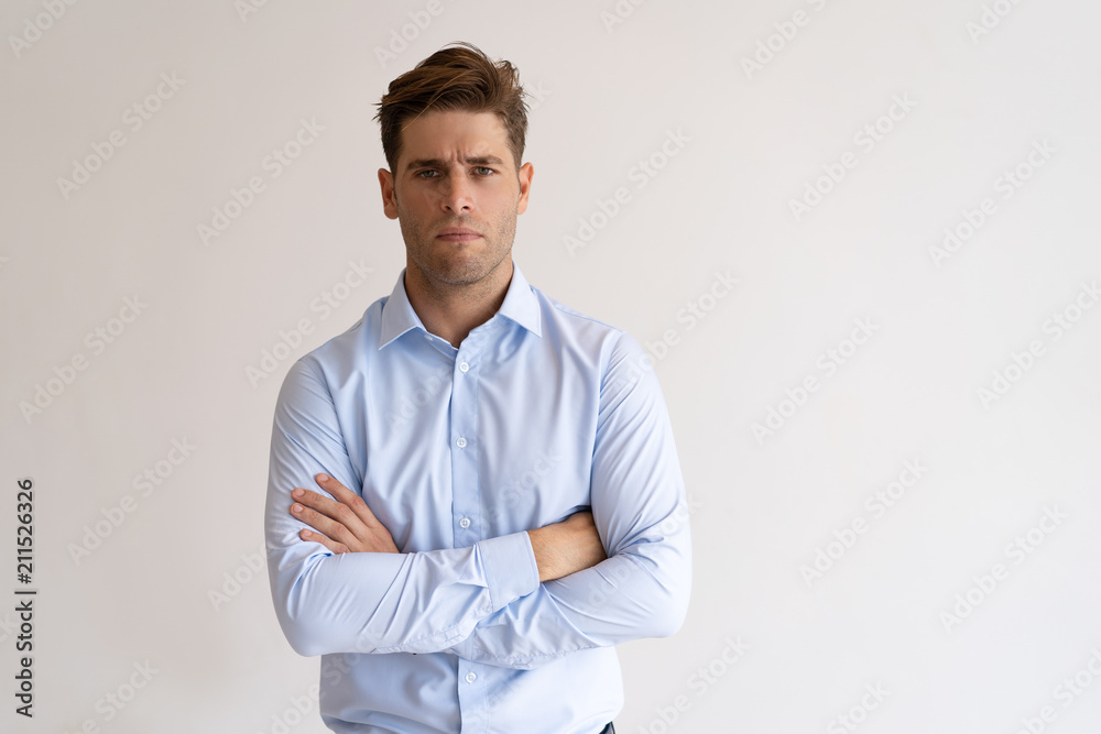 Tensed young man looking at camera. Serious handsome guy standing with ...