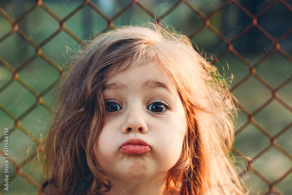 Foto de Portrait of cute little Girl with kissing lips looking at ...