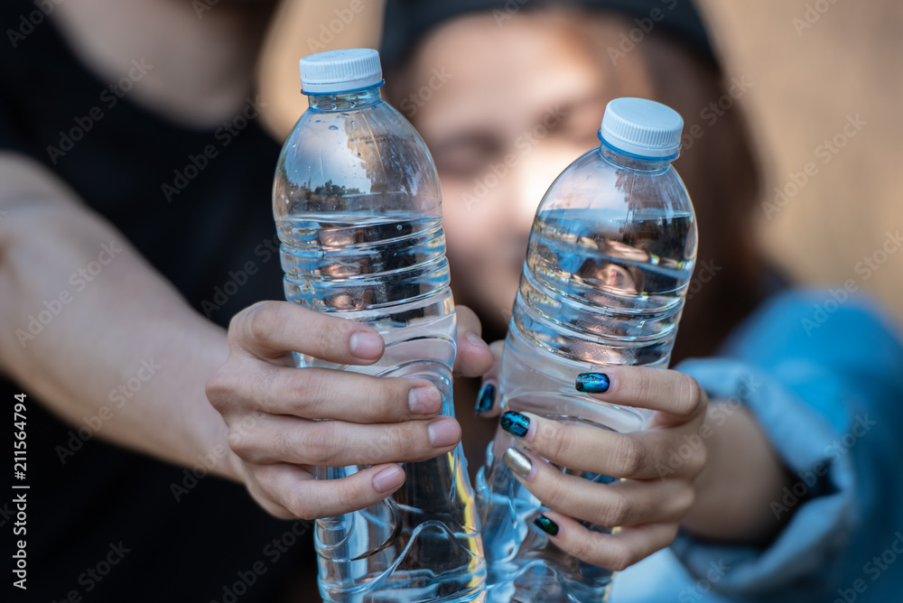 Couple of young people holding drinking water bottle on nature ...
