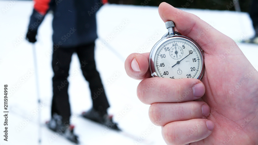 One person starting up a stopwatch in hand on a ski slope. Man pushing ...