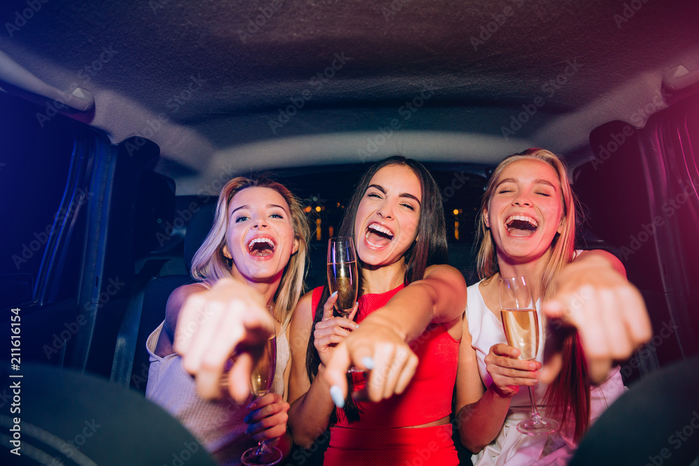 Happy and excited girls are sitting together in car. They are looking ...