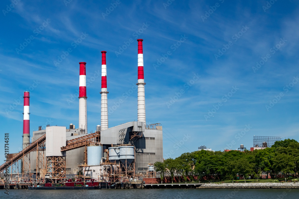 Power plant smoke stack towers contrast against blue sky background and ...