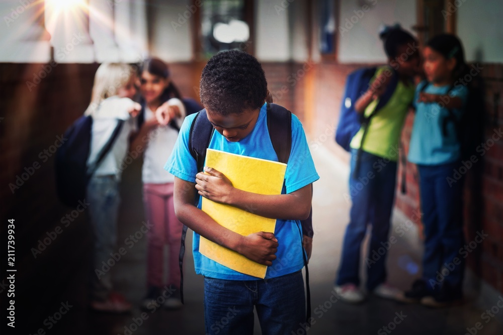 Sad pupil being bullied by classmates at corridor Photos | Adobe Stock