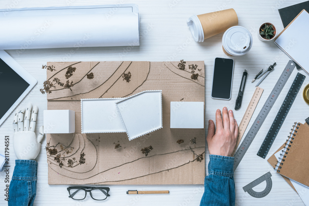 cropped image of male architect with prosthetic arm sitting at table ...
