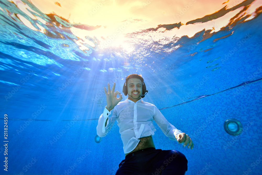 A young smiling man with a headset on his head swims and poses ...