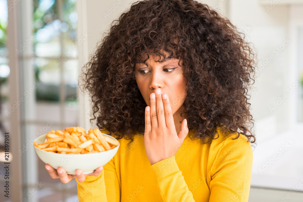 African american woman holding a plate with potato chips at home cover ...
