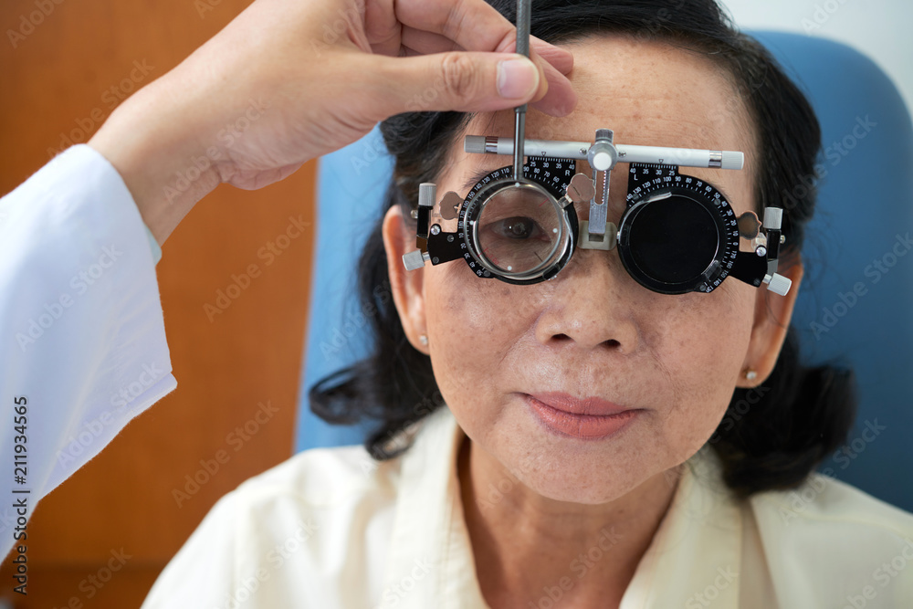 Crop hand of doctor setting special examining trial lens eyeglasses on ...