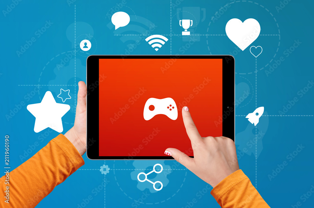 Boy's hand holding and touching the screen of tablet with game joystick ...