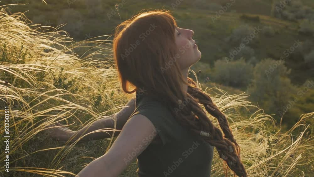 Young woman with red dreadlocks relaxing in fields during beautiful ...
