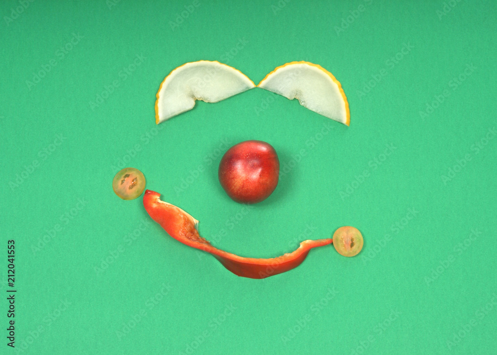 Clown face made with various raw vegetables, an emoticon on green ...