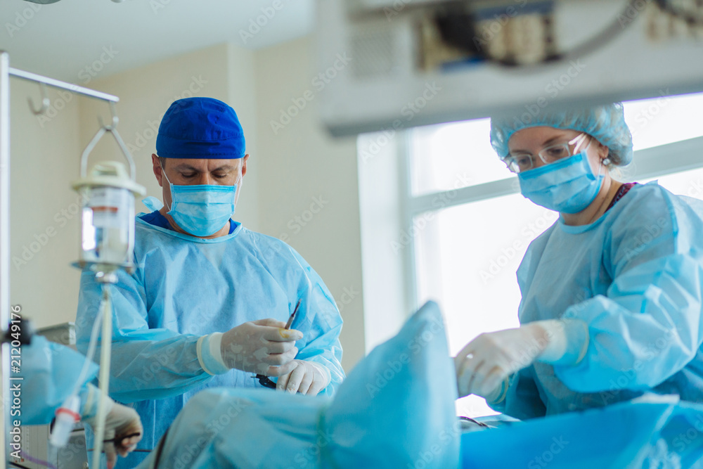 Male surgeon's holing the instrument in abdomen of patient. Female ...