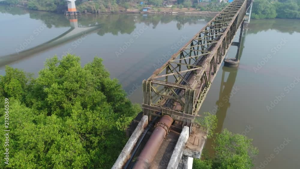 Aerial view. Rusty metal truss aqueduct over the water. Water supply through the pipe from one ...