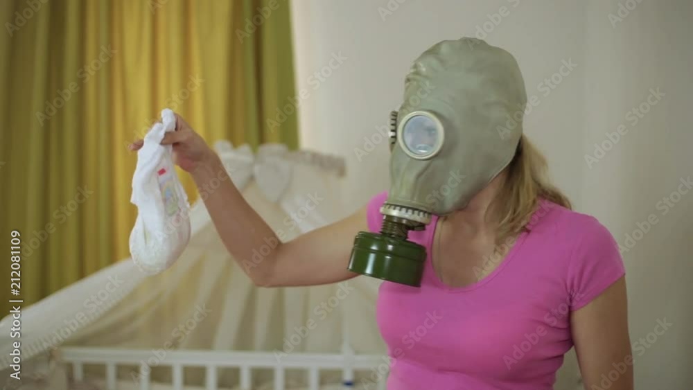 A woman in a gas mask and a dirty baby diaper. Young mother. Stock ...