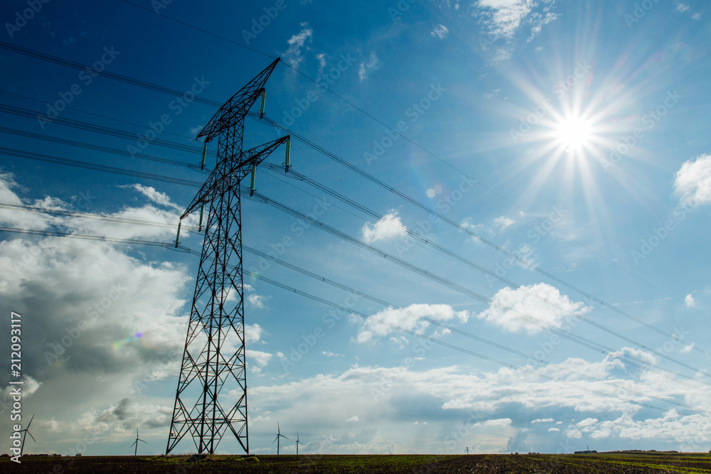 High voltage power lines and transmission towers with sunbeams in the ...