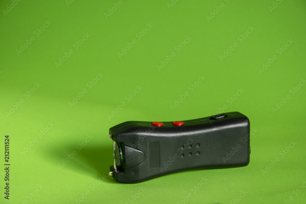 Electroshocker taser on a green background, safety and self-defense ...