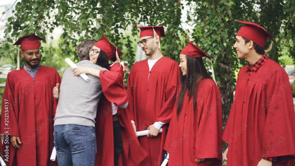 Bearded man proud teacher is congratulating graduates shaking hands and ...