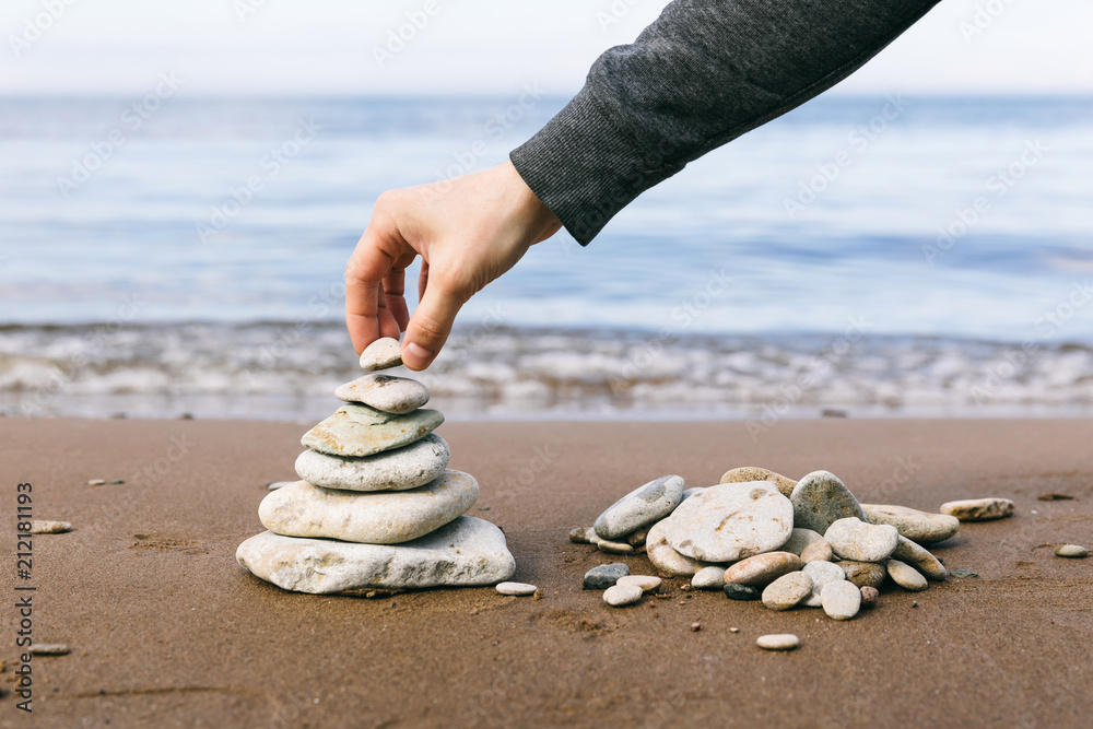 The stone in man's hand on the top of pyramid of stones for meditation ...